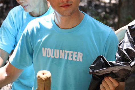 쓰레기 봉투를 들고 파란색 티셔츠를 입고 자원 봉사하고 생태 맨은 토지 오염 환경 문제를 줄이기 위해 쓰레기를 청소하고 집어 들고 세계 환경의 날 2명에 대한 스톡 사진 및