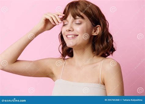 A Modest Shy Woman Stands On A Pink Background And Smiles Pleasantly