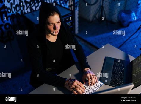 High Angle Side View Of Dangerous Hacker Man Wearing Hooded Typing Code On Wireless Keyboard
