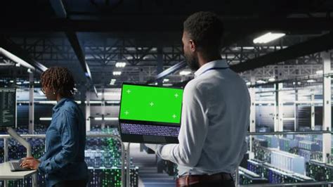 Technicians In Data Center Analyzing Performance Outputs On Green Screen Laptop Technology