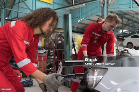 자동차 수리점에서 자동차 부품을 조립하는 남성 자동차 정비사 그룹 차고 작업장에 있는 차의 부속을 일하고 설치하는 기술공의 팀 25 29세에 대한 스톡 사진 및 기타 이미지
