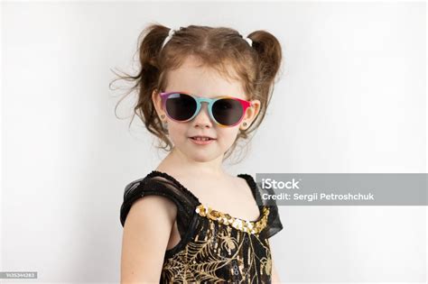 두 개의 포니 테일과 선글라스에 검은 색과 금색 드레스를 입은 어린 쾌활한 소녀 반쯤 된 슬픈 아이의 흰색 배경에 스튜디오 사진 2 3 살에 대한 스톡 사진 및 기타 이미지
