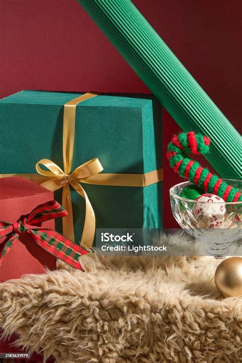 모피 깔개에 제품을 표시하기 위해 중간에 빈 공간이 있는 크리스마스 사진 템플릿 그 옆에는 노엘 공 양모 사탕 지팡이 선물 상자가 들어 있는 유리 컵이 있으며 뒤에는 빨간색