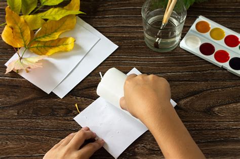 아이는 촛불을 그리고 수채화는 나무 배경에 단풍을 그립니다 어린이를위한 종이공예품 어린이 예술 프로젝트 10월에 대한 스톡 사진