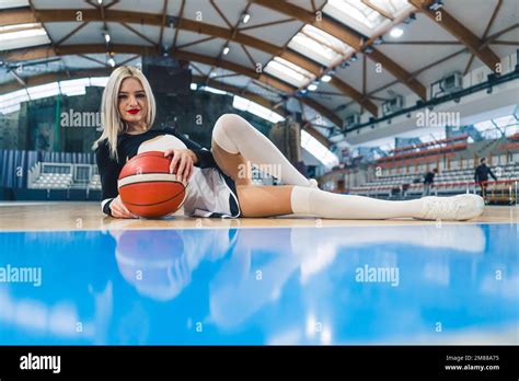 An Attractive Cheerleader Is Captured Lying On The Floor Of An Indoor Court In A Flirtatious And