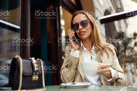 선글라스를 끼고 카페 테라스에 앉아 커피를 마시며 전화 통화를 하는 아름다운 여자 25 29세에 대한 스톡 사진 및 기타 이미지