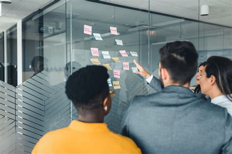 유리 벽에 차트를 작성하고 고집을 부림으로써 창조적 인 기업 사무실에서 작업 계획과 목표를 개발하는 공식적인 마모의 심각한