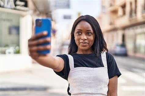 거리에서 스마트 폰으로 셀카를 만드는 자신감 미소 젊은 아프리카 계 미국인 여성 Brand Name Smart Phone에 대한
