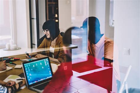 스마트 캐주얼 웨어를 입은 젊은 이들이 유리 벽 뒤의 미팅 테이블에 앉아 있는 스타트업 프로젝트 개발에 협력했습니다 공통 작업에 협력 하는 남성과 여성 디자이너의 그룹 20