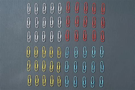 사무실 업무 나 교육을위한 빨간색 노란색 흰색 및 파란색 색상의 종이 클립의 네 섹션은 어두운 긁힌 콘크리트 테이블에 놓여있습니다 맨 위 보기 강철에 대한 스톡 사진 및