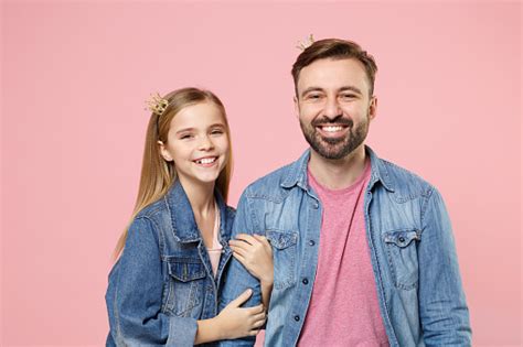 캐주얼 한 옷을 입고 수염을 기고한 남자는 귀여운 아이 아기 소녀와 재미를 가지고 있습니다 파스텔 핑크 벽 배경에 고립 된 아버지 작은 아이 딸 가족 부모 어린 시절 개념을