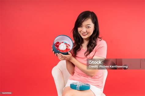 선물 상자를 들고 빨간 배경 위에 고립된 작은 하트로 흰 장미 꽃을 보여주는 아름다운 아시아 여성 발렌타인 데이 개념입니다 감정의 미소 갈색 머리에 대한 스톡 사진 및 기타