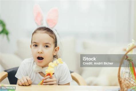 그녀의 머리에 토끼 귀에 꽤 귀여운 어린 소녀 그녀의 손에 막대기에 달콤한 부활절 토끼를 들고 카메라에 깜짝 보고 가정 생활에 대한 스톡 사진 및 기타 이미지 Istock