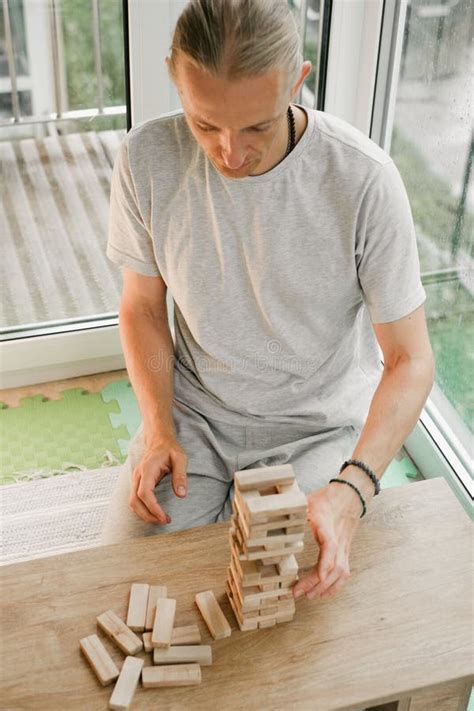 Man Carefully Stacking Wooden Blocks In A Game Of Skill At Home Stock