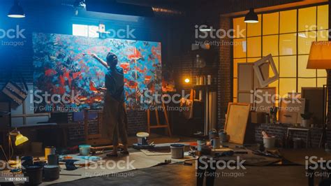 재능있는 여성 예술가가 페인트 브러시로 활발하게 그림을 그리며 유화의 현대 걸작을 만듭니다 눈에 띄는 색상의 큰 캔버스와 창조적 인 스튜디오 개념에 대한 스톡 사진 및 기타