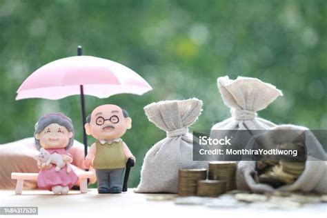 뮤추얼 펀드 사랑 부부 선배와 자연 녹색 배경에 동전 돈 더미로 우산을 들고 손 미래를 준비하고 연금 은퇴 개념을 준비하기 위해 돈을 저축 0명에 대한 스톡 사진 및 기타