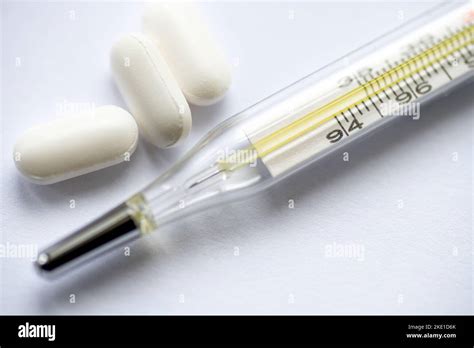Close Up Of An Analogue Thermometer With Some Medicine Tablets Isolated In White Background