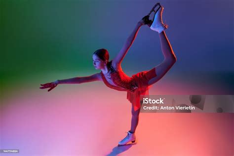 스포티한 십대 소녀 주니어 여성 피겨 스케이팅 선수의 초상화는 네온 불빛의 그라데이션 녹색파란색 배경 위에 격리된 빨간색 무대 의상 스케이트를 타고 있습니다 그레이스 뷰티