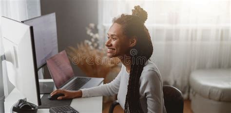 Smiled Cheerful Female Web Expert Sitting At Desk In Living Room Coding