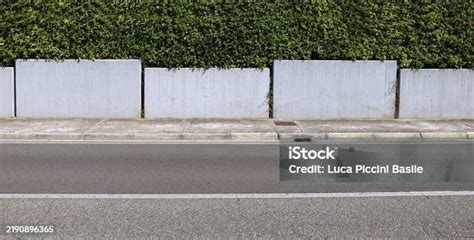 회색으로 칠해진 벽으로 만든 집 울타리는 블록으로 나뉘어 있고 뒤에는 높은 울타리가 있습니다 콘크리트 보도와 앞 거리 0명에