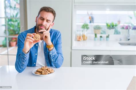 초콜릿 칩 쿠키 심각한 얼굴 질문에 대 한 생각을 먹고 잘생긴 남자 아주 혼란 스러운 아이디어 먹기에 대한 스톡 사진 및 기타 이미지 Istock