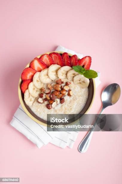 바나나 딸기 아몬드 헤이즐넛 버터를 분홍색 배경에 넣은 오트밀 그릇 아침 식사 최고 전망을 위한 뜨겁고 건강한 요리 0명에 대한