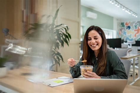 노트북으로 작업하는 동안 책상에서 건강한 점심을 먹는 웃는 사업가 20 29세에 대한 스톡 사진 및 기타 이미지 20 29세 25 29세 30 39세 Istock