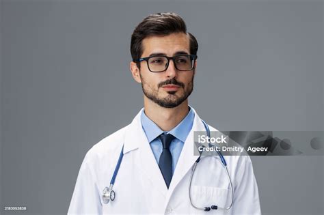 흰 가운과 안경을 쓰고 청진기를 든 진지한 의사 남자가 회색의 고립된 배경 복사 공간 텍스트를 위한 공간 건강의 공간에서 카메라를 바라봅니다 25 29세에 대한 스톡 사진