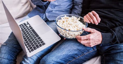 알아볼 수 없는 아들과 집에서 노트북을 들고 팝콘을 먹고 있는 그의 선배 아버지 실내에서 2 세대 사진 Unsplash의 팝콘 이미지