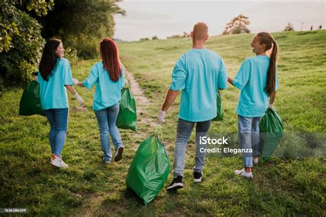 도시 잔디밭에서 쓰레기를 제거하는 야외 청소부 여자와 남자가 비닐 봉지를 들고 걸어가는 뒷모습 야외 쓰레기 수거 개념 Charitable Foundation에 대한 스톡