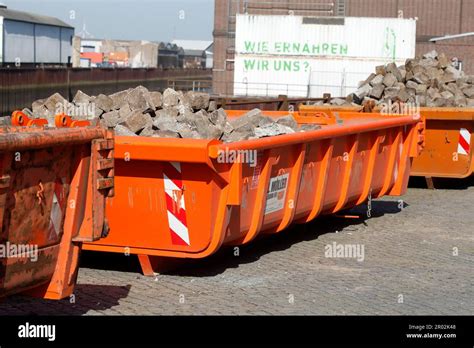 Container Orange Skip For Construction Waste Standing On The Road In The Harbour Construction