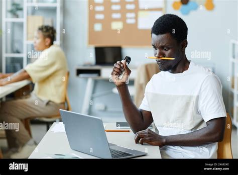 Portrait Of Young Black Man Using Multiple Objects As Fidget Toys While