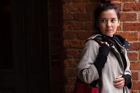 혼합된 경주 서 벽돌 벽 옆의 젊은 아름 다운 여성 모델의 이미지와 빨간색 섬유 가방 회색 코트 입고 거리에 대한 스톡 사진 및 기타 이미지 Istock