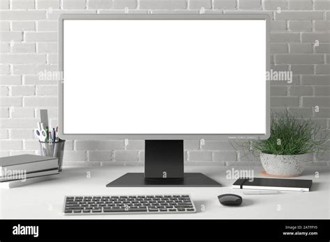 Workspace With Blank Computer Monitor White Screen Mock Up On The White Desk Near White Brick