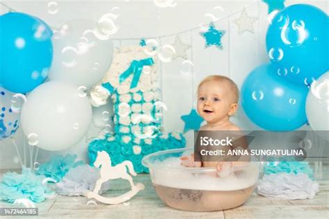 아기 소년은 풍선 휴일 및 장식 개념이 있는 파란색으로 된 축제 생일 장식으로 비누 방울과 거품이 있는 욕조에서 목욕합니다 6 11 개월에 대한 스톡 사진 및 기타 이미지
