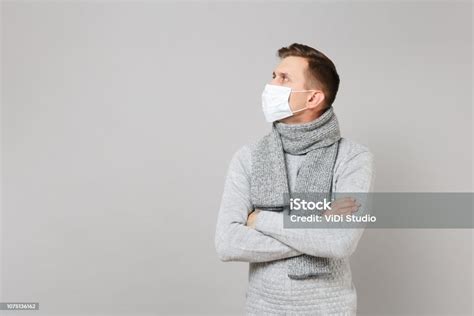 회색 스웨터에서 젊은 남자에 고립 된 회색 배경 접혀 스카프 메 마른 얼굴 마스크 보고 옆으로 손을 잡고 건강 한 생활 습관 병 아픈 질병 치료 추운 계절 개념 복사 공간을