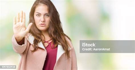 플러스 크기 젊은 여자는 손의 종 려를 가진 정지 노래를 하 고 격리 된 배경 위에 겨울 코트를 입고 아름 다운 얼굴에 부정적이