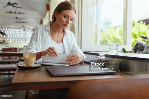 비즈니스 카페에서 여성 원격 작업 노트북에 뭔가를 쓰는 노트북캐주얼 옷과 안경을 입은 소녀 여름 방학에 편안한 장소에서 창조적