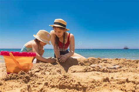 Sisters In Sun Hats Building A Sandcastle On A Beach Stock Image