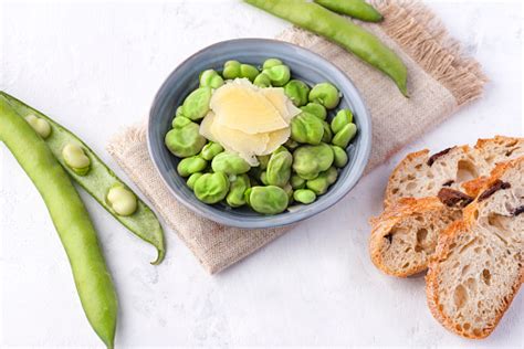 소박한 흰색 배경에 얇게 썬 파마산 치즈를 곁들인 삶은 넓은 콩 또는 파바 콩 클로즈업 건강한 채소 점심 정원에서 식탁까지 봄철 야채와 콩과 식물 요리법 건강한 생활방식에