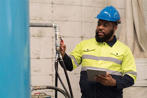 산업 공장에서 공기 압축기의 탱크를 검사하는 디지털 테이블과 함께 일하는 공장 남성 엔지니어 노동자 남성 기술자 유지 보수 공기 압축기 기계 40 44세에 대한 스톡 사진