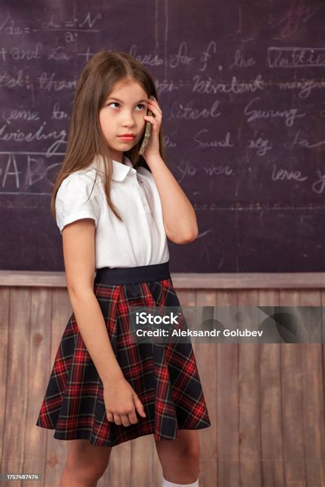 교복을 입은 7살 여학생이 칠판에 휴대전화를 걸며 어리둥절한 표정을 짓고 있다 교실에서 아이 모델 학생 소녀 학교 학습 교육 개념 광고 텍스트 공간 복사 6 7 살에 대한