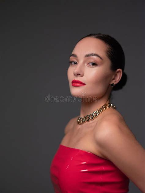 Portrait Of Young Beautiful Brunette Woman In Red Latex Dress With