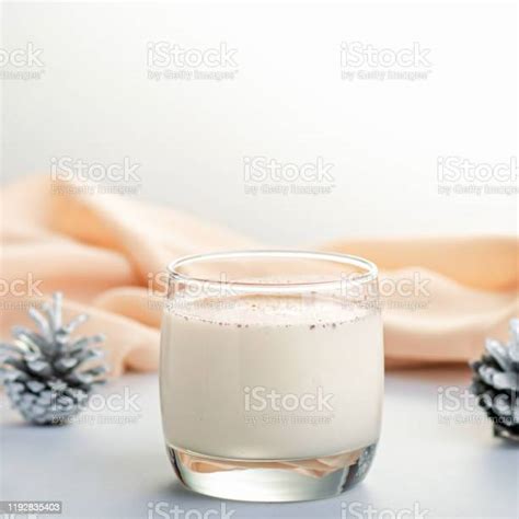 계란 알코올 강판 육두구와 계피 클로즈업 복사 공간을 가진 전통적인 크리스마스 칵테일 Eggnog 베이지 색 장식 불타는 등불과 소나무 콘이있는 회색 테이블에 달콤한 전통