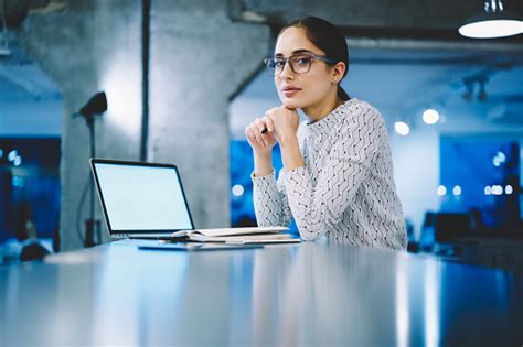 정보 분석을 위한 모의 화면이 있는 랩톱 컴퓨터를 사용하여 실험실에서 연구하는 안경에 있는 영리한 여성 과학자의 초상화 진료소에서 카메라를 보는 학생 만들기 시험 Stem