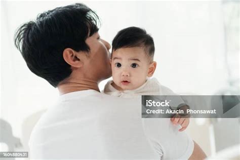 아버지의 행복 사랑스러운 아기를 손에 들고 있는 젊은 아시아 아빠가 집 창가에 서 있다 갓난아기와 함께 시간을 보내는 사랑하는