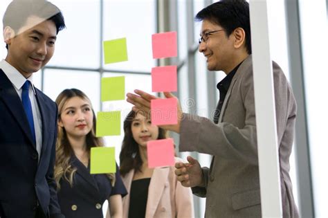 A Professional Man And Woman Stand Together Engaged In A Brainstorming Session Using Document