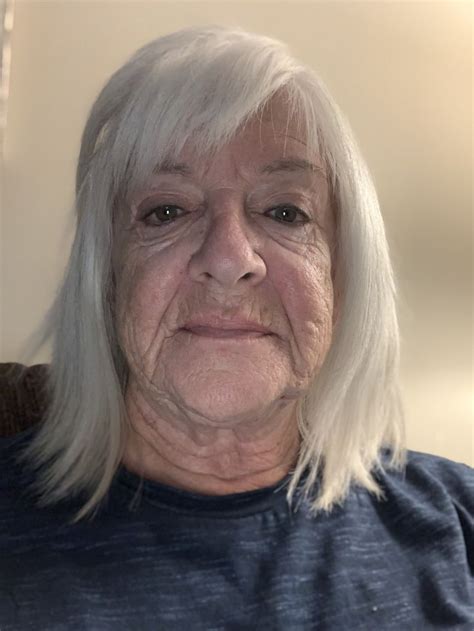 An Older Woman With White Hair And Bangs Looking At The Camera While