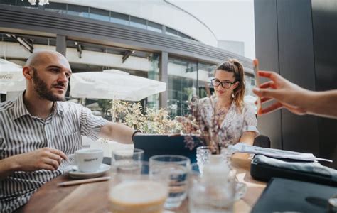 Startup Team Discussing And Brainstorming Ideas During Business Meeting At A Modern Outdoor Cafe