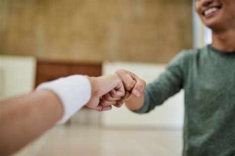 실내 체육관이나 스포츠 코트에서 훈련 경기 중에 주먹으로 부딪히는 두 선수의 손을 클로즈업합니다 유나이티드 스포츠맨들이 서로 동기를 부여하고 팀으로서 성공을 거두고